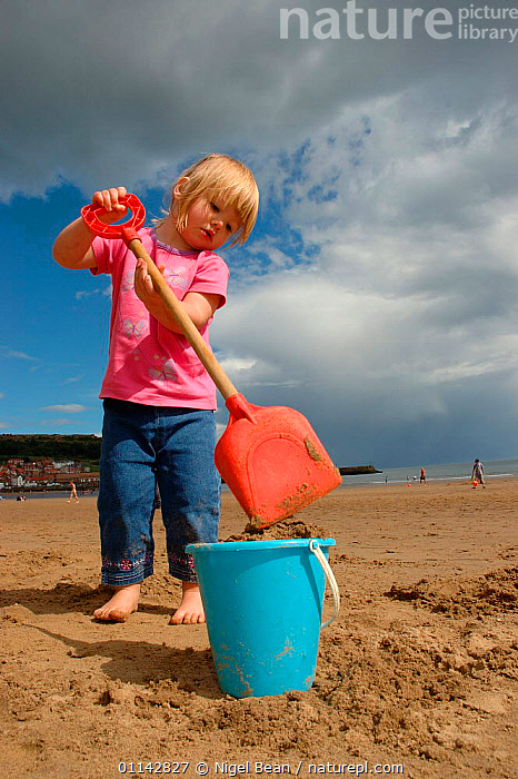 Stock photo of Young girl digging sand at seaside, Scarborough, North ...