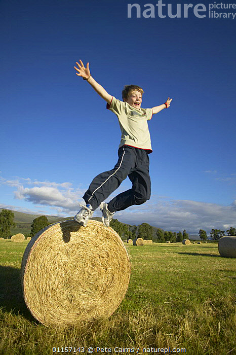 Stock photo of Boy jumping off round hay bale, Scotland, UK. Available ...