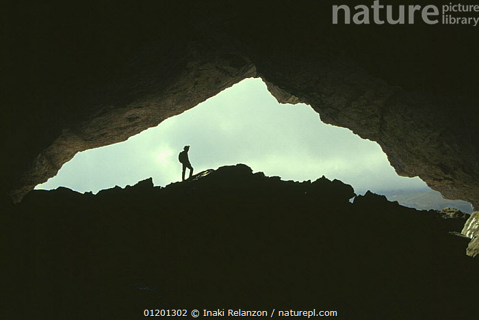 Stock photo of Potholer silhouetted at exit to underground cave system ...