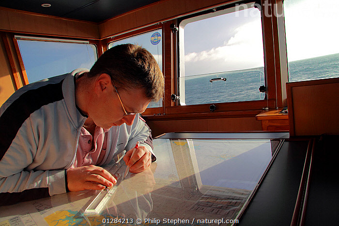 Stock photo of Fishing skipper doing chartwork in the wheelhouse of his ...