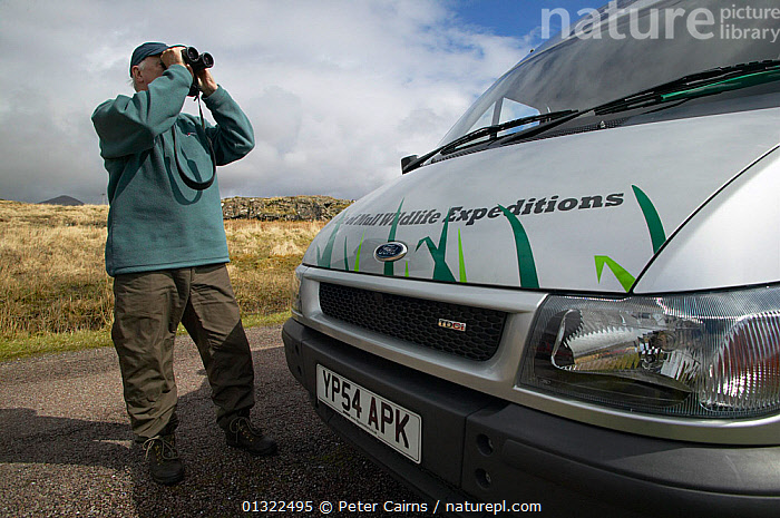 Stock photo of Wildlife spotter looking through binoculars from beside ...