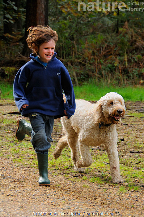Stock photo of Boy running with pet dog (Canis familiaris) a ...
