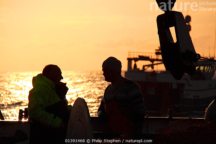 Stock photo of Silhouetted trawlermen on board their vessel on the ...