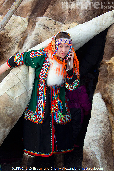 Stock photo of Young Nenets woman using a mobile phone emerging from ...